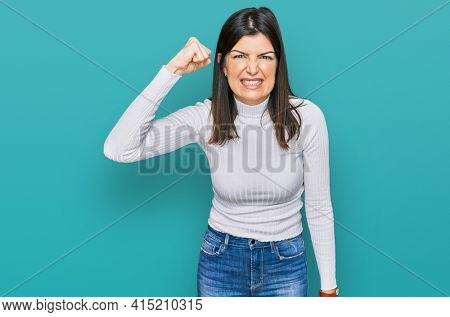 Beautiful brunette woman wearing casual clothes angry and mad raising ...