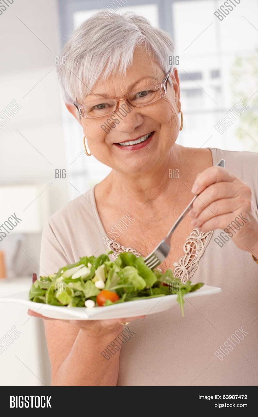 Woman Eating Salad While Laughing