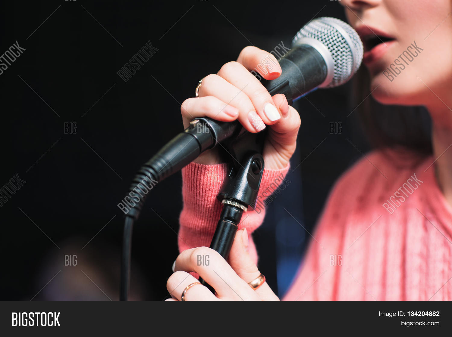 Microphone and unrecognizable female singer close up. Cropped image of ...